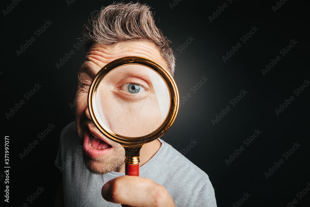 man see through magnifying glass on the black backgrounds. Big man eye ...