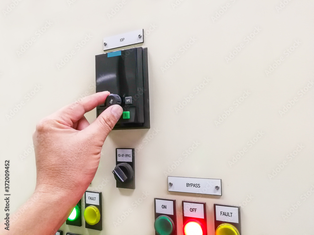 Hand holding the control panel of the industrial plant and pushing or ...