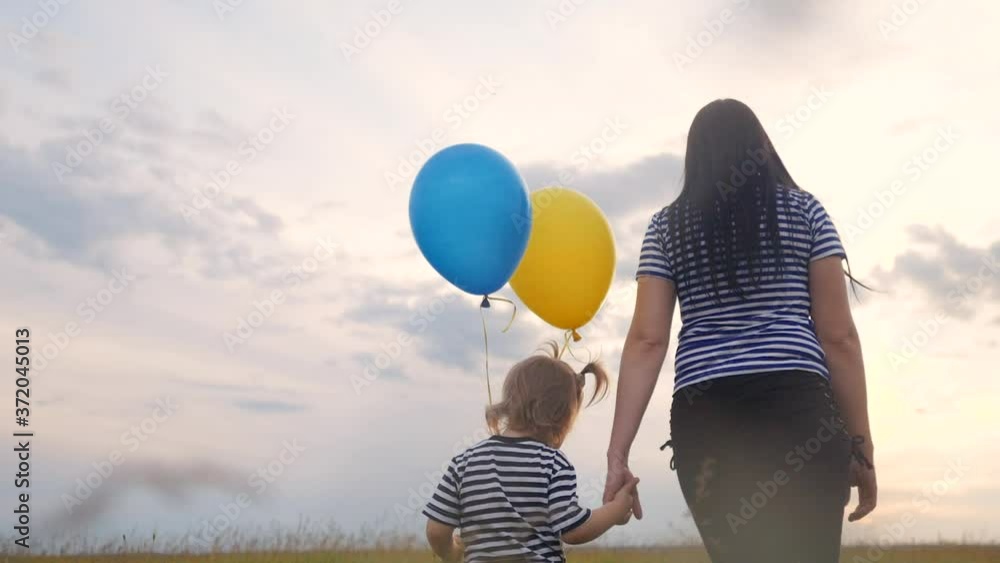 happy family daughter and mom go strolling in the park with balloons ...
