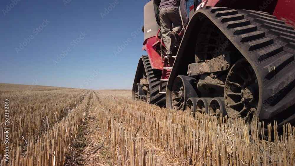 Young Caucasian male upset farmer exits big red tractor machine and ...