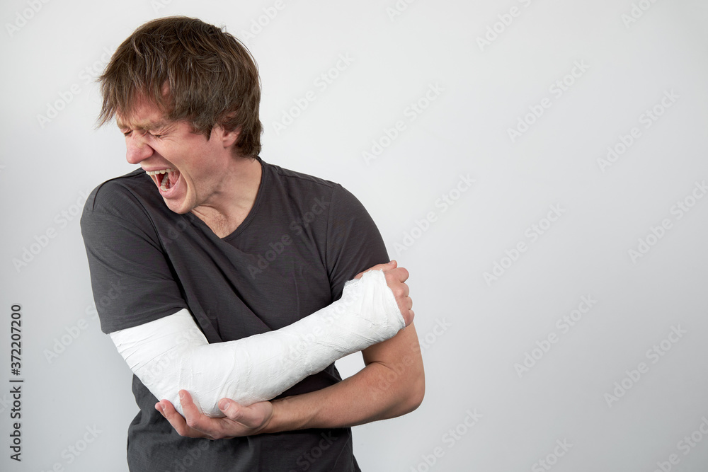 Young unhappy crying caucasian man with plaster cast on his hand ...