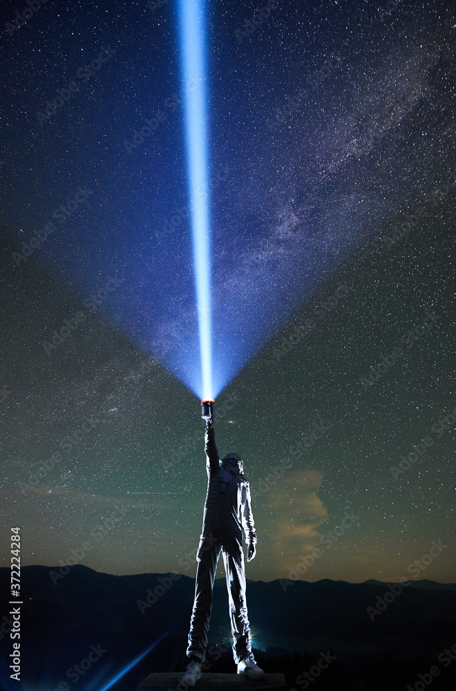 Space traveler in space suit and helmet illuminating beautiful starry ...
