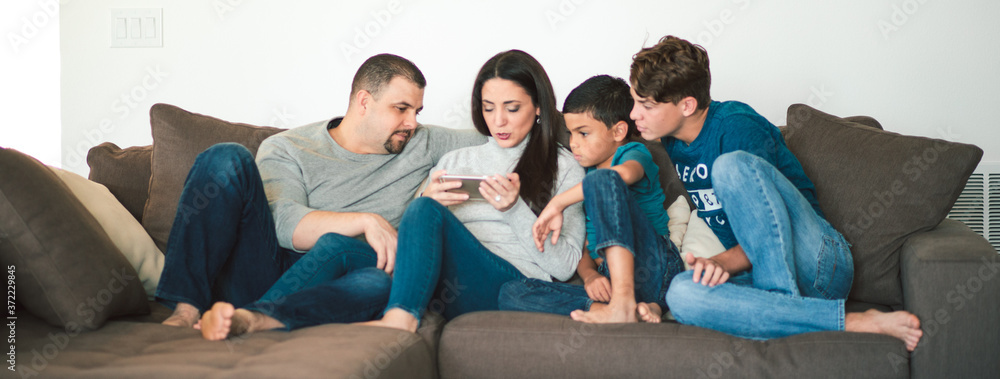 Family in a living room sitting on the couch having a good time while ...
