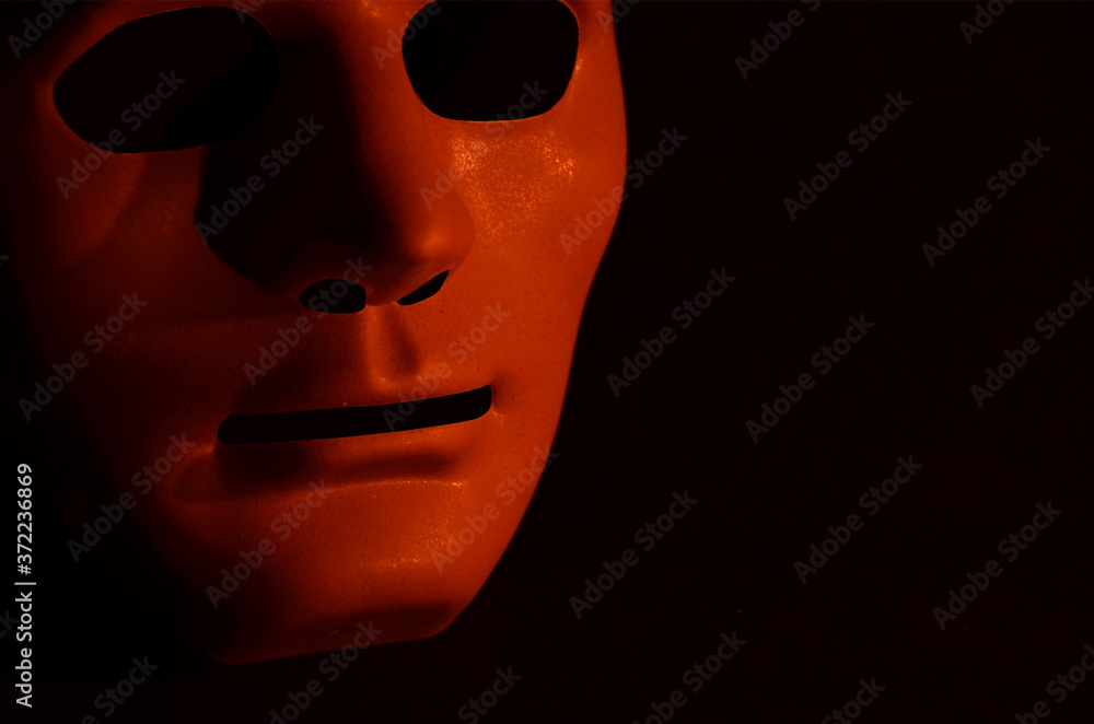 Scary red mask in the light on black background Stock Photo | Adobe Stock