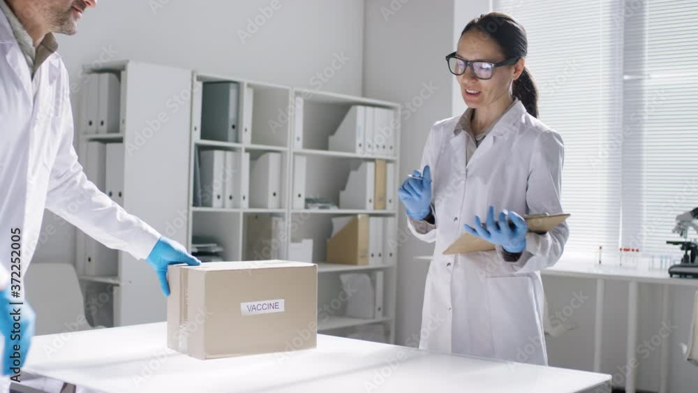 Sequence of shots of female doctor in lab coat recieving box of covid ...
