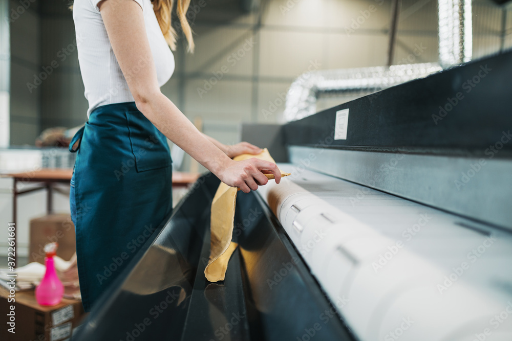 Young laundry worker pats the linen on the automatic machine at the dry ...