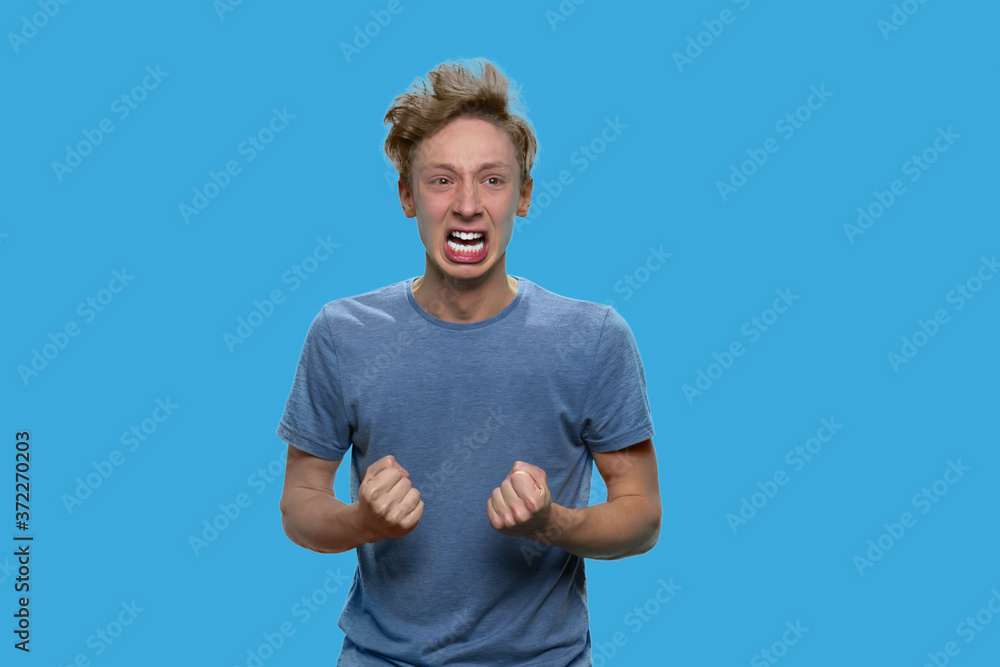 Crazy irritated teen boy is shouting on blue background. Emotional ...