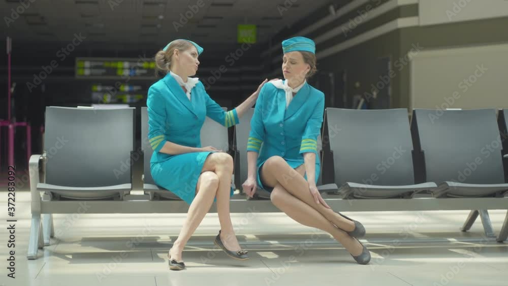 Wide shot of young beautiful stewardess calming down colleague in ...