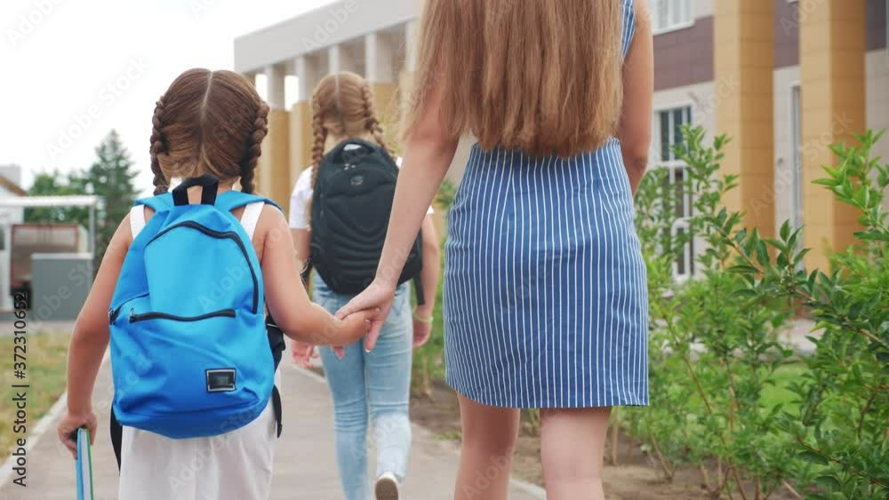 parent leads to school child with backpack back view. kids go to school ...
