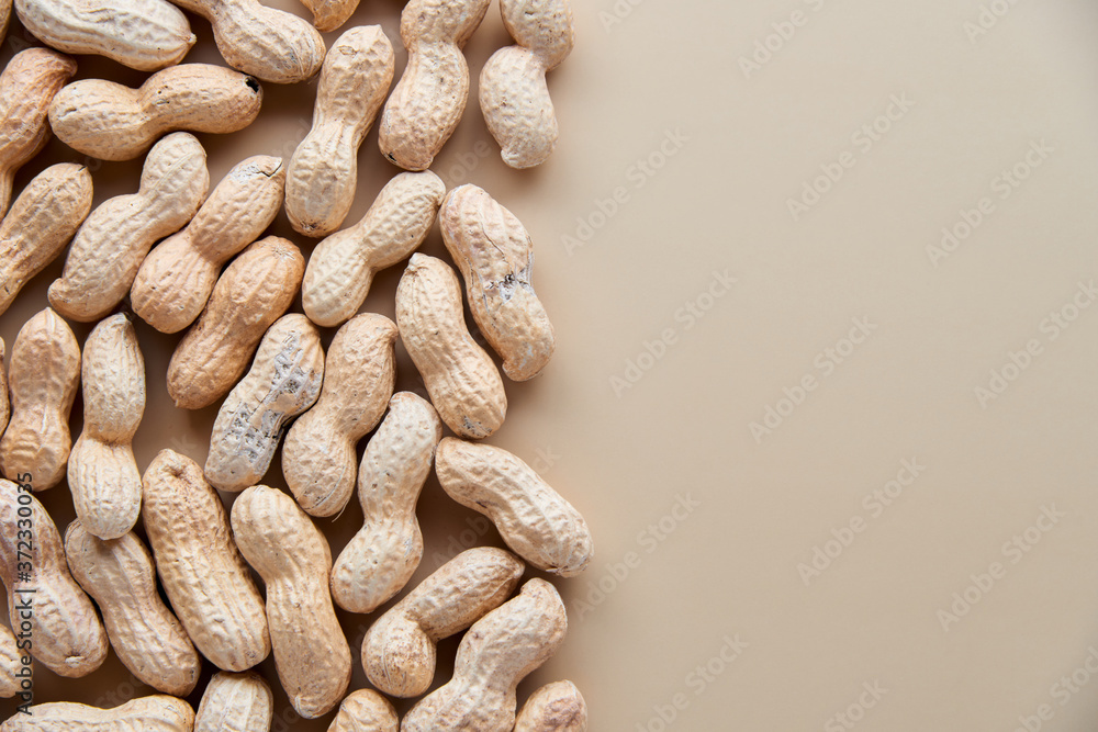 Roasted unsalted unpeeled peanuts in shell isolated on beige background ...