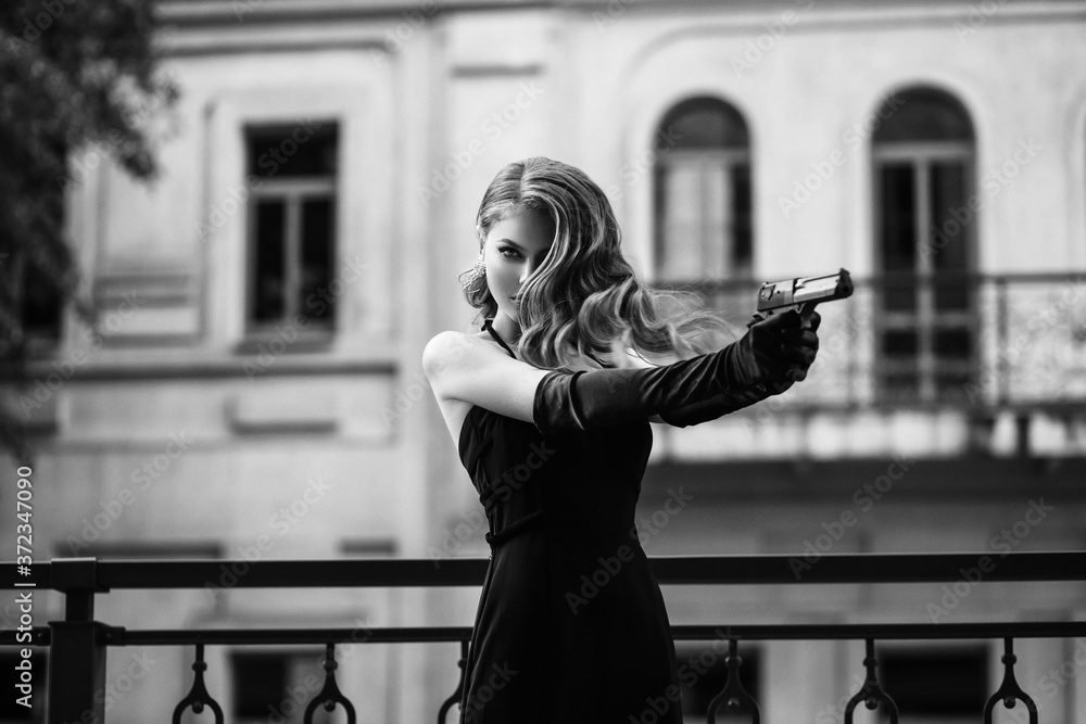 Beautiful young girl in an elegant dress. Woman holding a gun in her ...