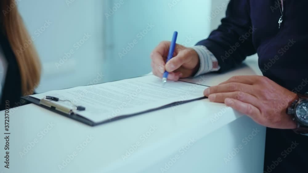 Close up hands man fiil the form at the reception in clinic hospital ...