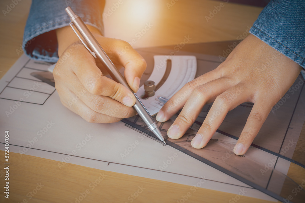 Architect or engineer holding a pen, measuring with a triangular ruler ...
