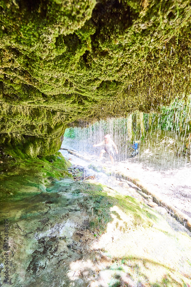 Waterfall flowing over a mossy rock with cave behind in the Canyon ...