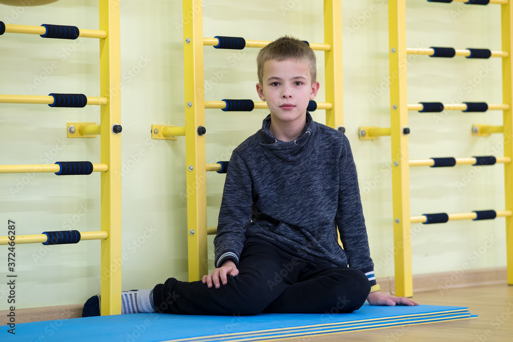 Young child boy sitting and relaxiong on the floor inside sports room ...