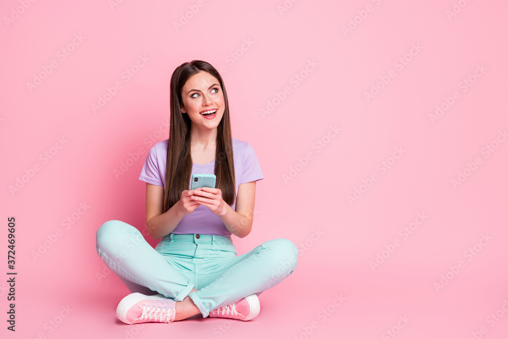 Full size photo of excited girl sit floor legs crossed use cellphone ...