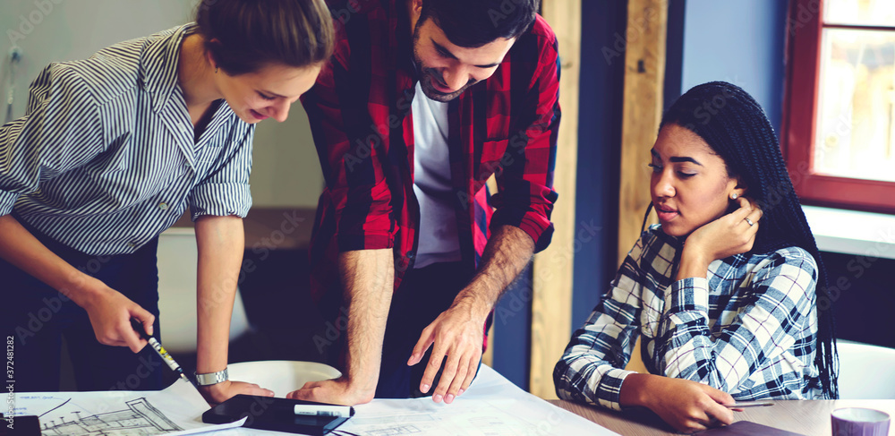 Group of male and female students trying to copy blueprint of modern ...