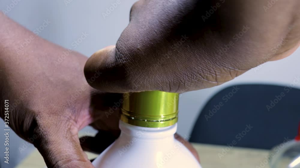 close up macro view of African american black hand twisting a cap off a ...