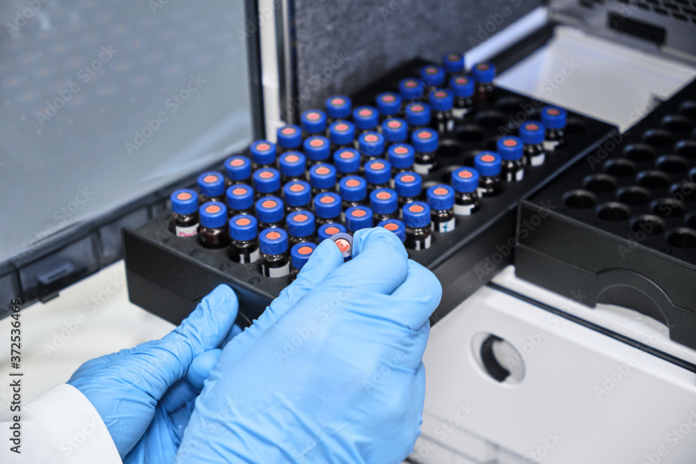 Chemist putting vial with a sample into autosampler of HPLC system ...