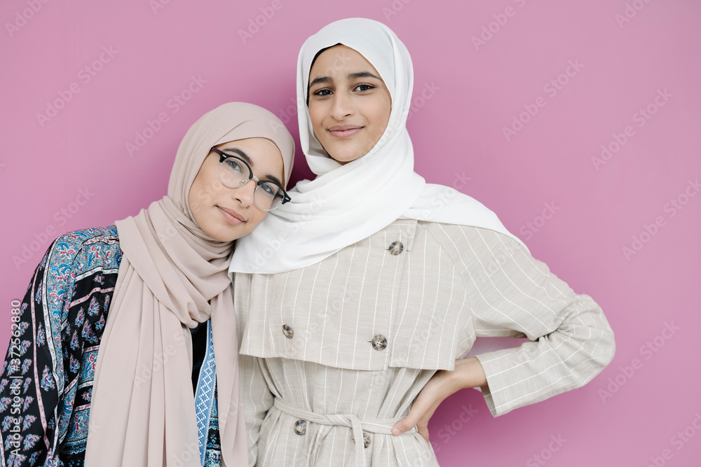 Muslim sisters standing together against purple background Stock Photo ...