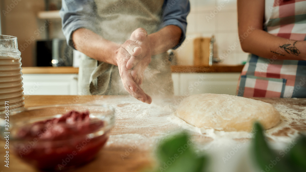 Cropped shot of couple making pizza together. Young man in apron ...