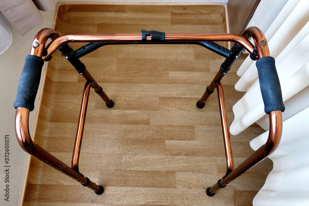 A foldable and adjustable metallic reciprocal walking frame at a corner ...