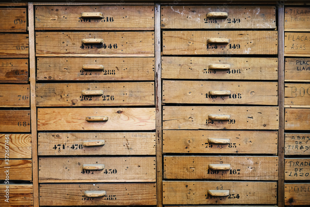 Archive representing identical light brown wooden drawers with ...