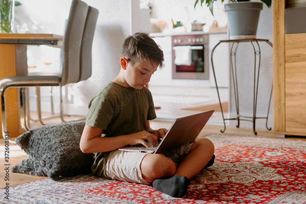 Foto de Serious little boy sitting on floor with legs crossed and ...