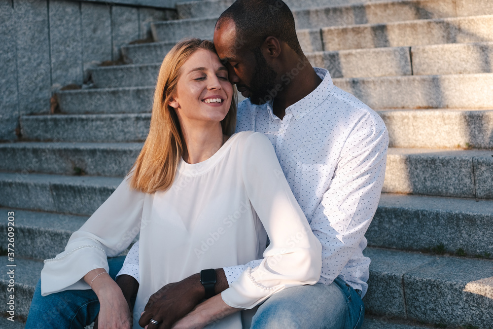 Content black boyfriend sitting on street stairs behind smiling ...