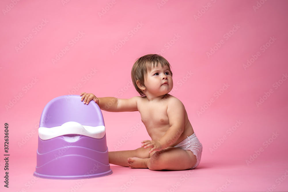 Cute baby in a diaper sitting on a potty. Toilet and potty training ...