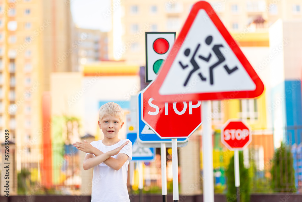 a child stands at a STOP sign and holds his hands in a cross, traffic ...