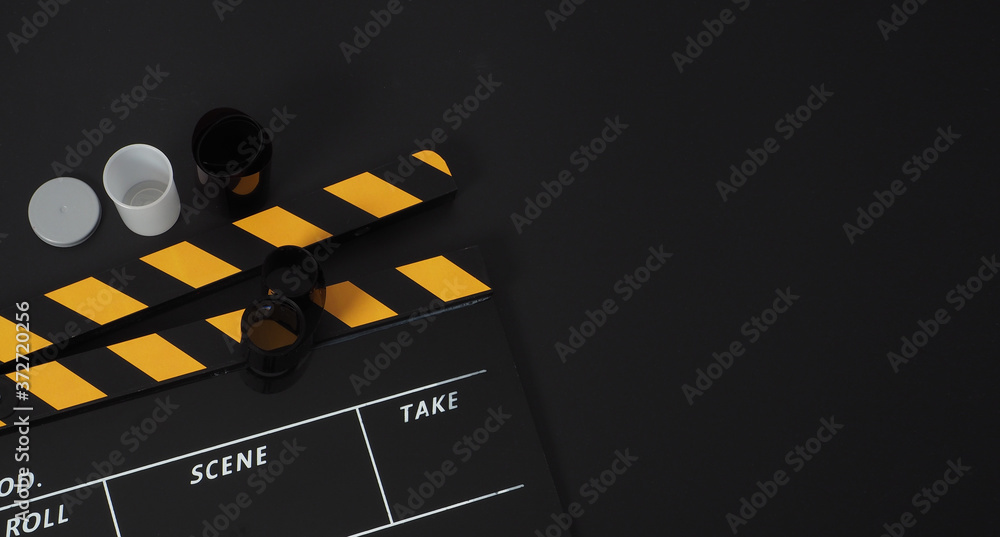 Clapper board and film roll on black background. It use in movie and ...