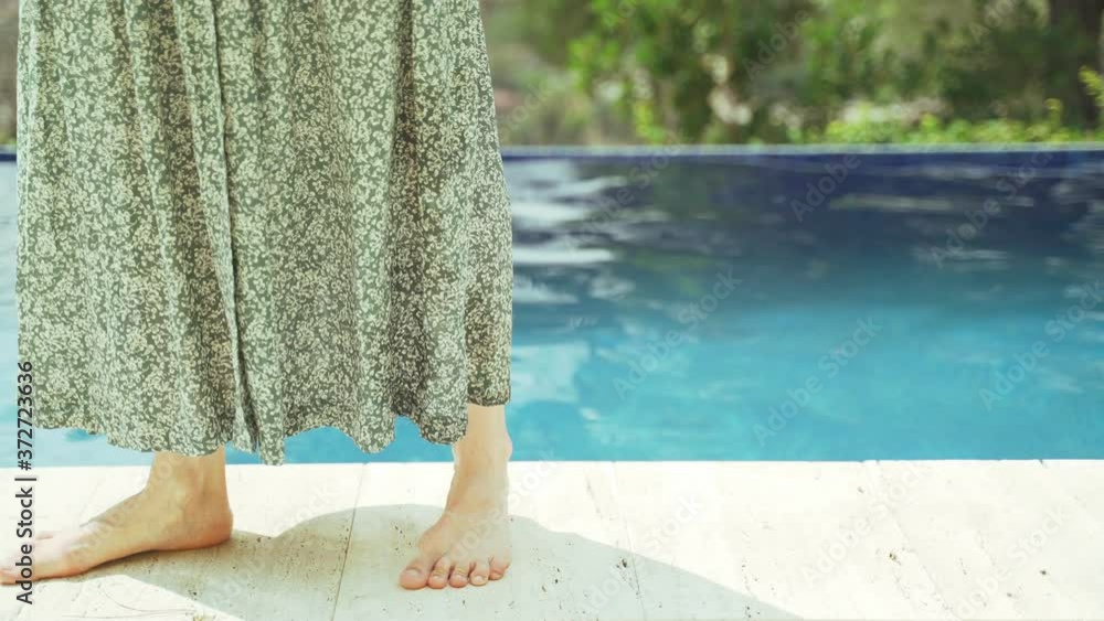Vidéo Stock Barefoot girl in a green dress is walking along the edge of ...