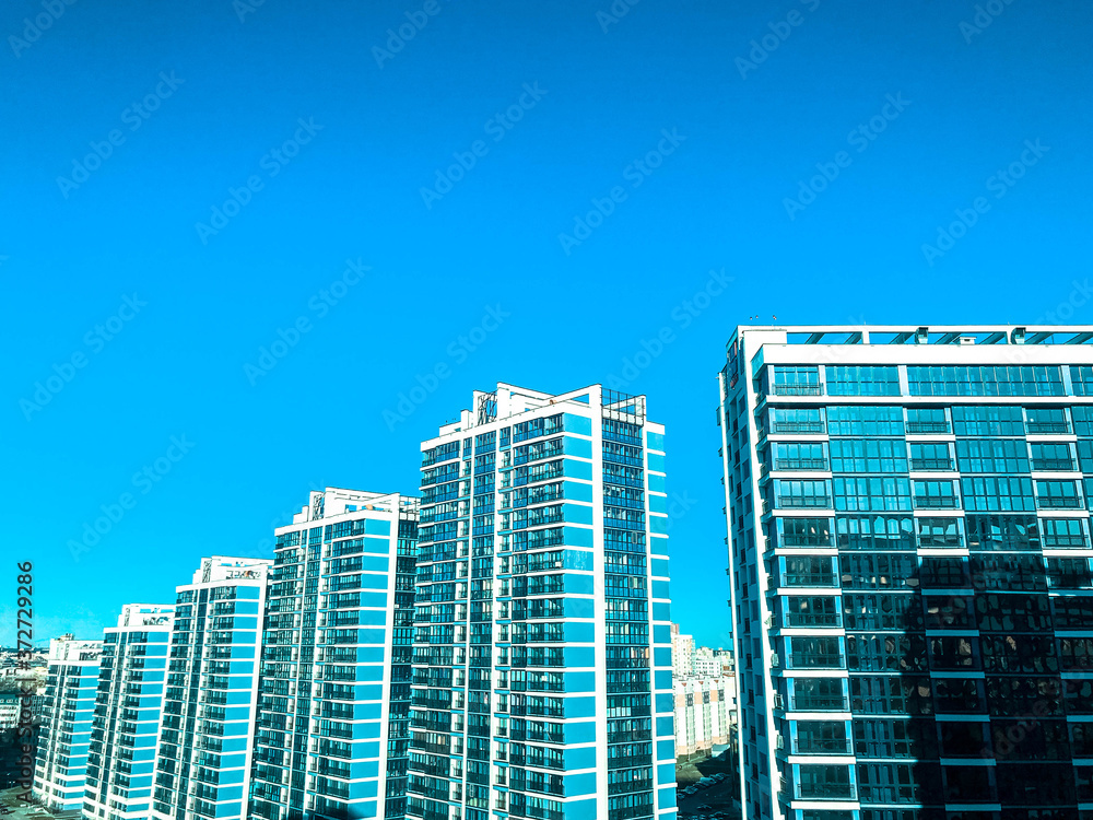 the tops of tall blue glass houses against the pale blue sky. unusual ...