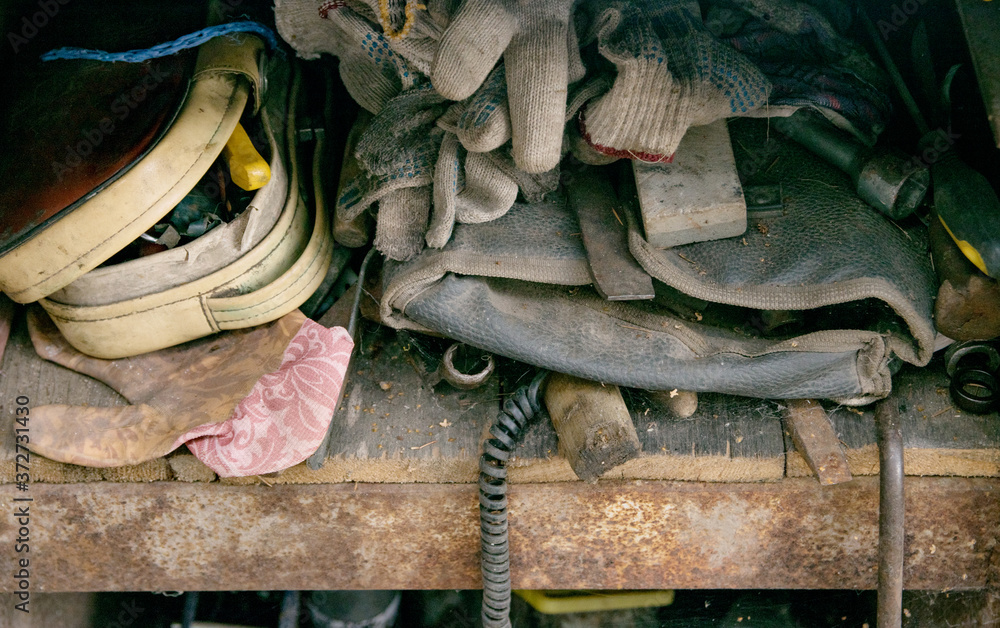 Old abandoned trash from tools lies on the shelf of a rusty workbench ...