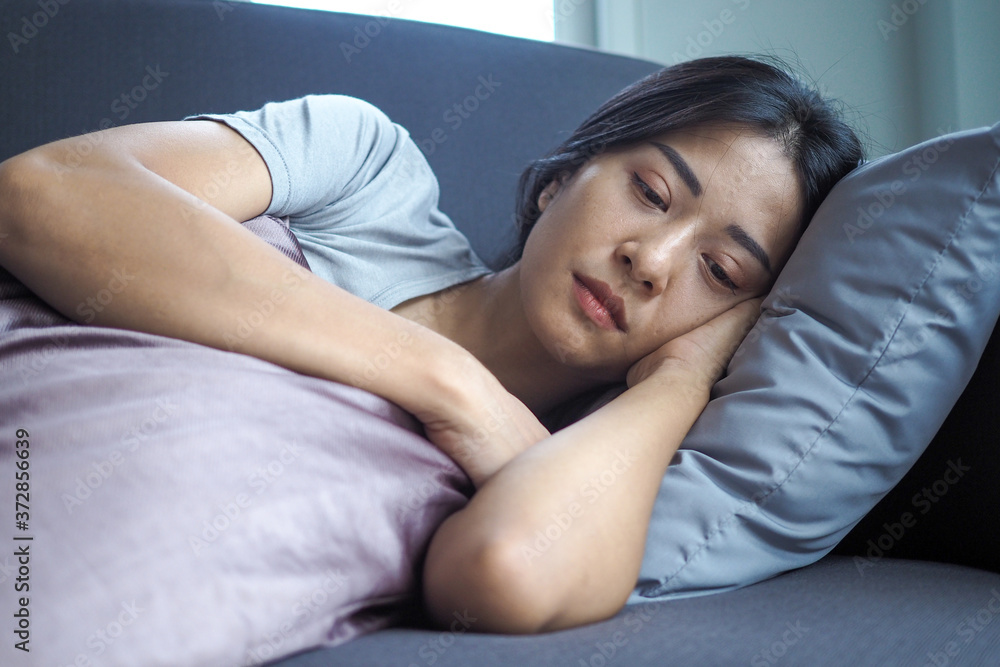 A depressed Asian woman cuddles a pillow and feels sorry after an ...