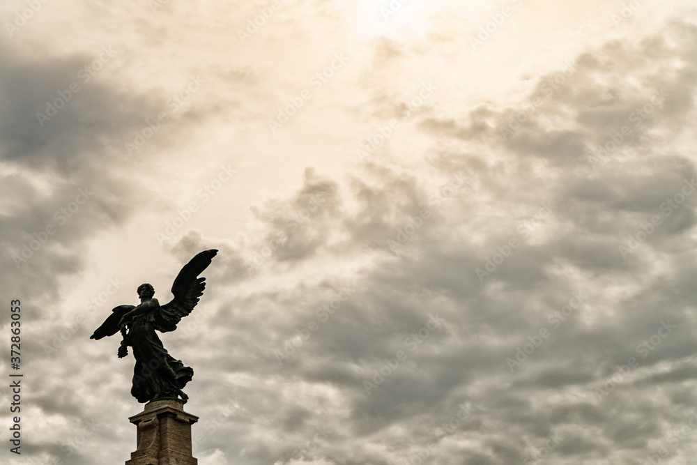 Statue of an angel in Rome and clouds background with sun rays as ...