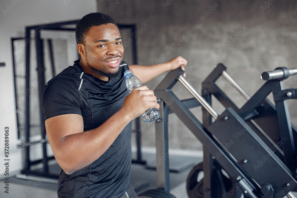 Sports man in the gym. A black man performs exercises. Guy in a black t ...