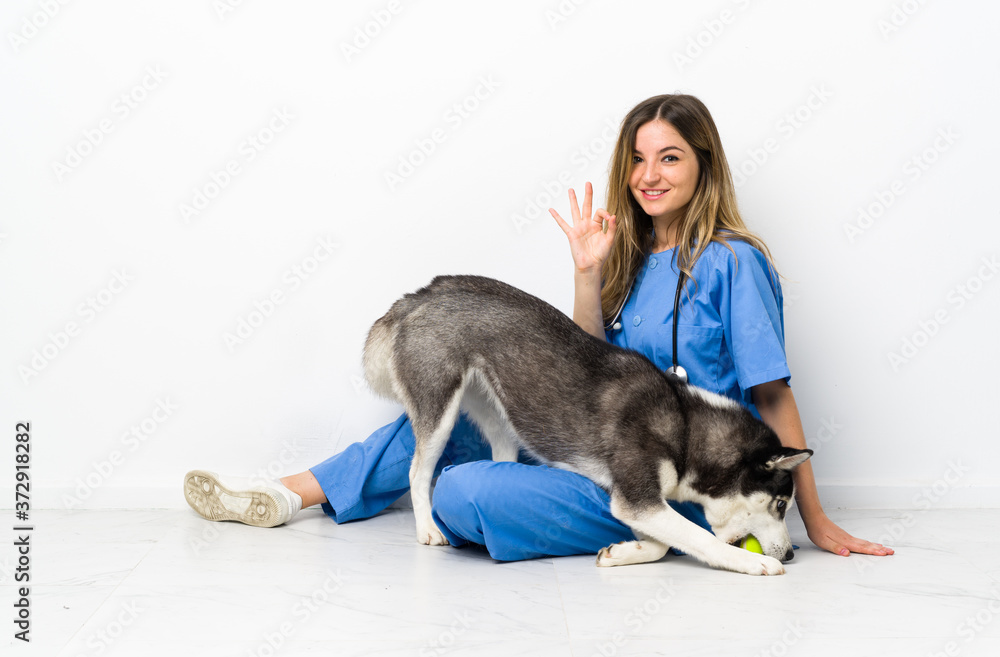 Veterinary doctor with Siberian Husky dog sitting on the floor showing ...
