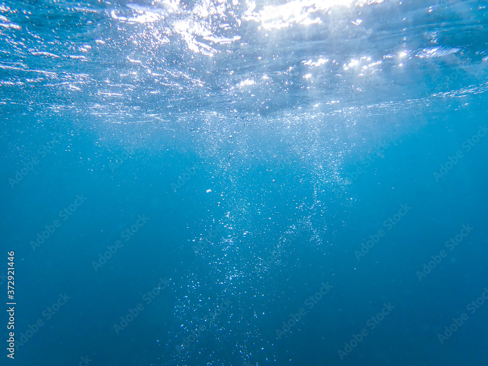 sea bubbles . Blue sea waves from underwater with bubbles. Light rays ...