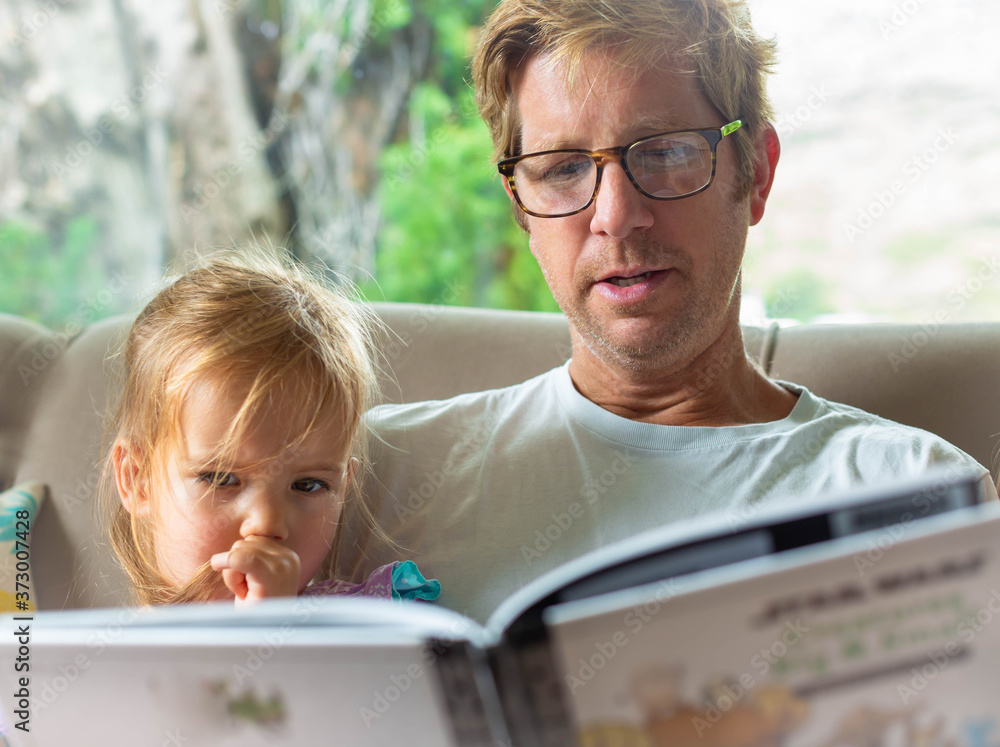 Dad reading a book to his daughter at home. Home school. Stock Photo ...