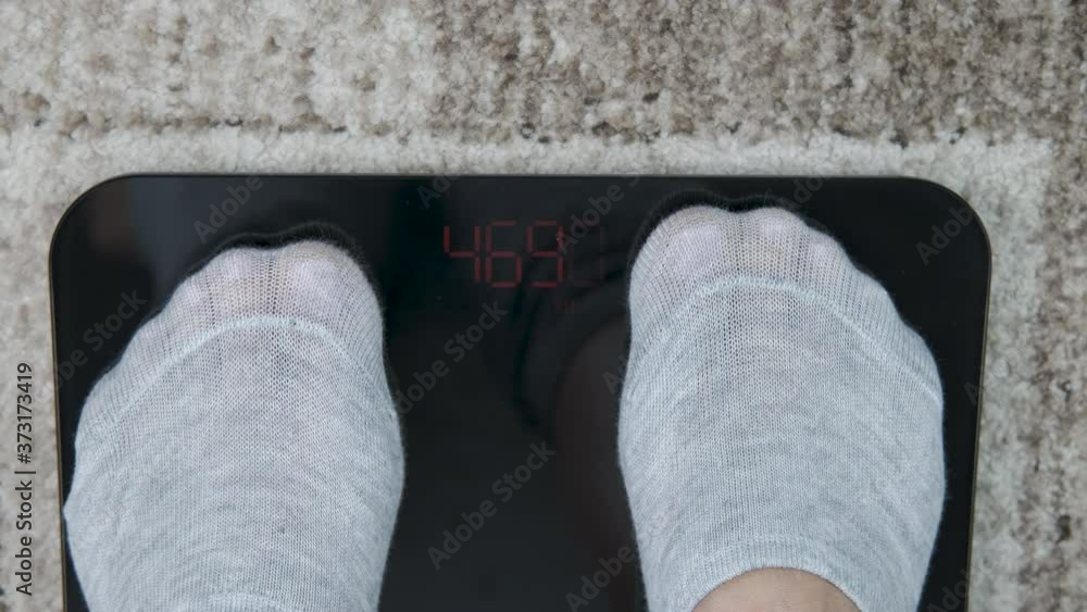 Vidéo Stock A thin woman on a scale. Women's feet stand on the floor ...