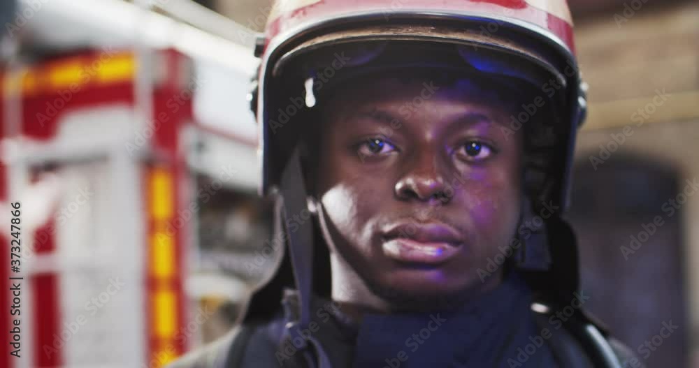 Portrait of African American firefighter approaches from fire van with ...