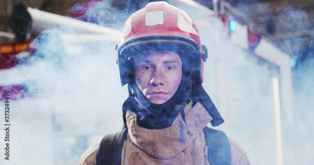 Portrait of fireman in helmet and gull equipment standing next to car ...