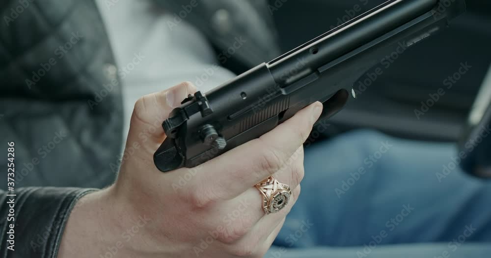 Unrecognizable gangster with pistol in car. From above anonymous ...