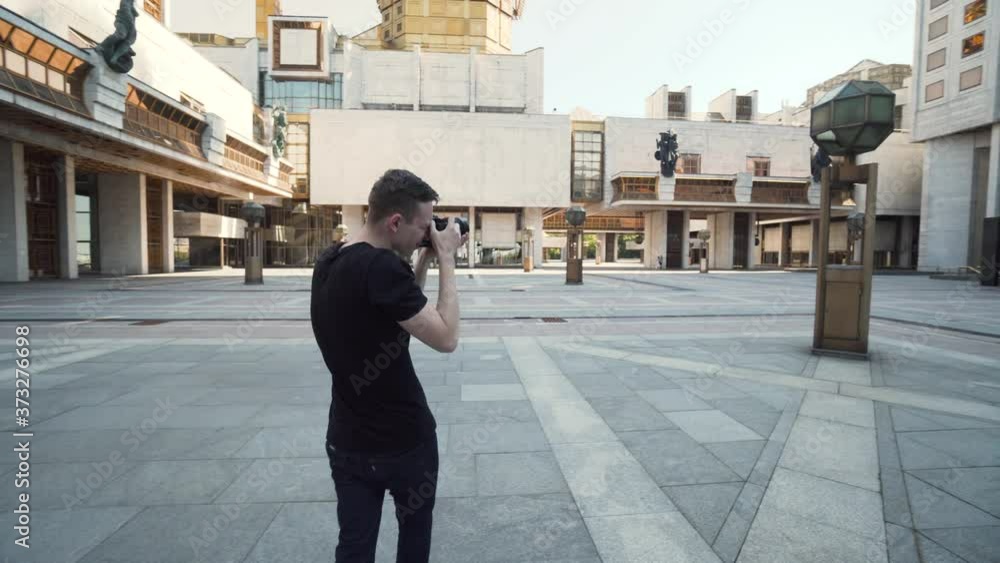 Young man photographs popular buildings in city. Action. Guy takes ...