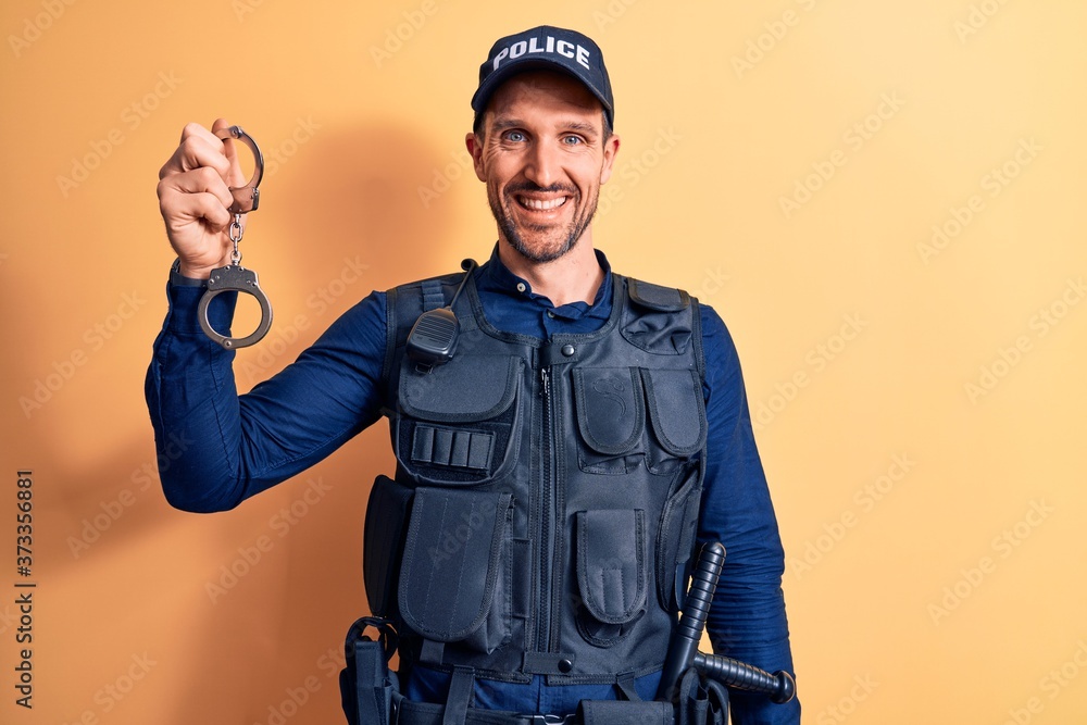 Handsome policeman wearing uniform and bulletprof holding handcuffs ...