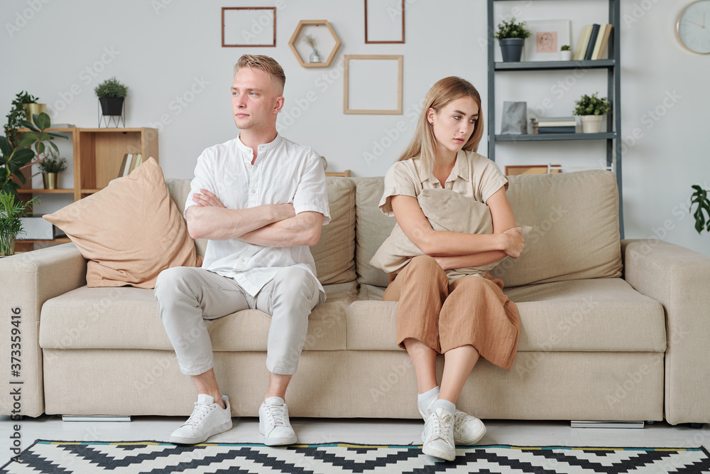 Young man and woman with arms crossed by chest expressing sadness and ...