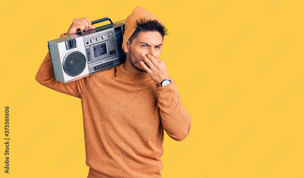 Handsome latin american young man holding boombox, listening to music ...
