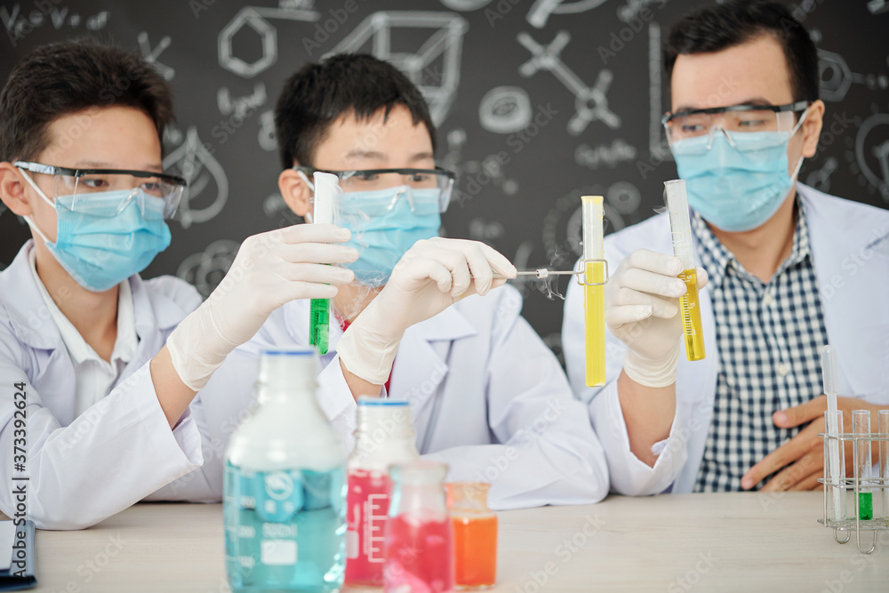 Science teacher and students in medical masks and rubber gloves holding ...